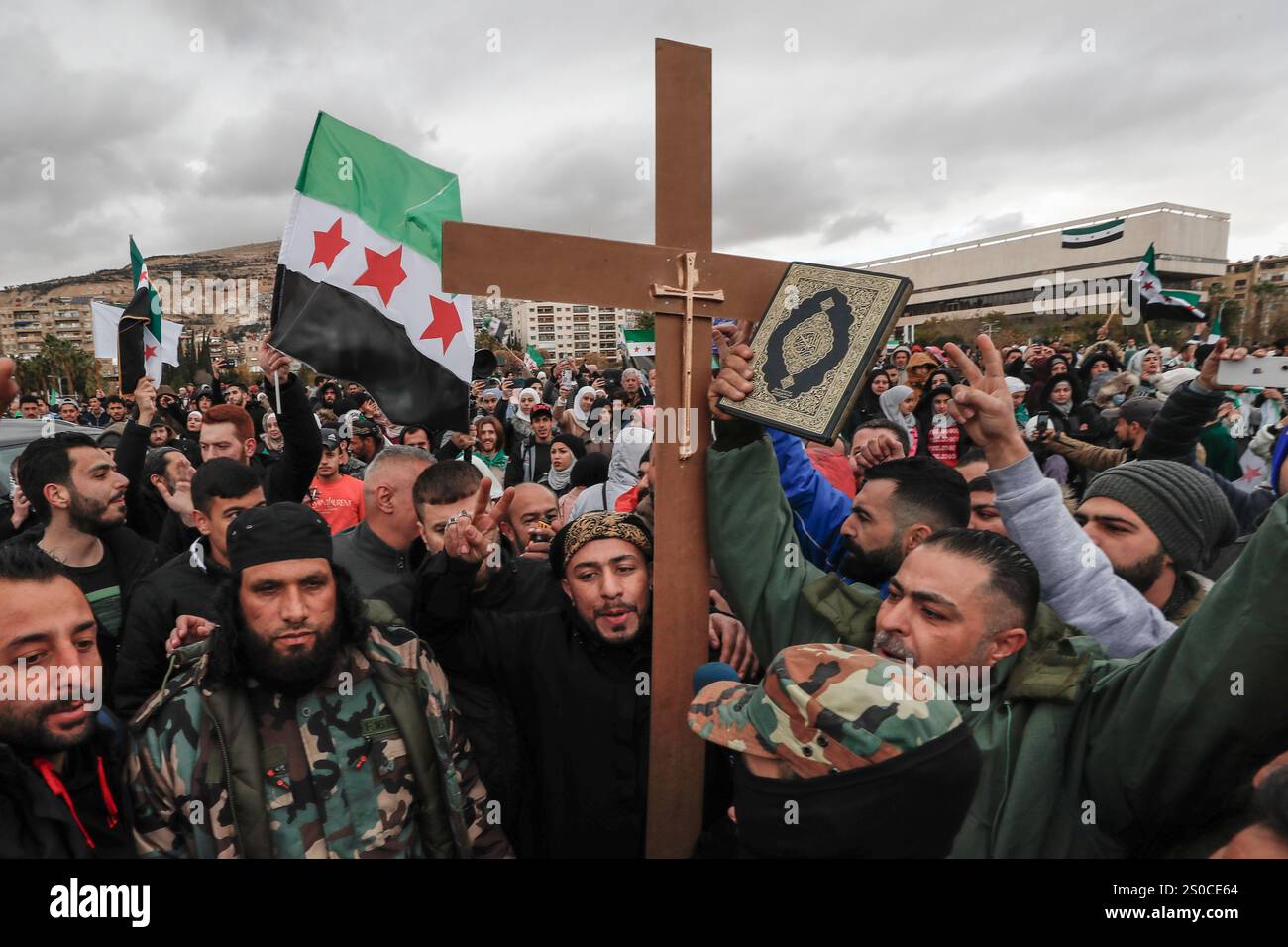 Syrians hold a copy of the Quran next to a Christian cross during a ...