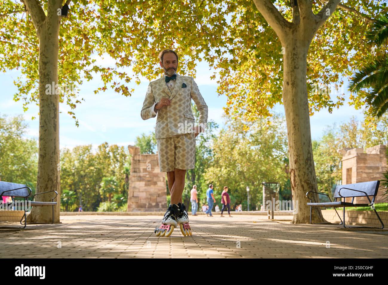 Man in patterned suit posing confidently on rollerblades in a park ...