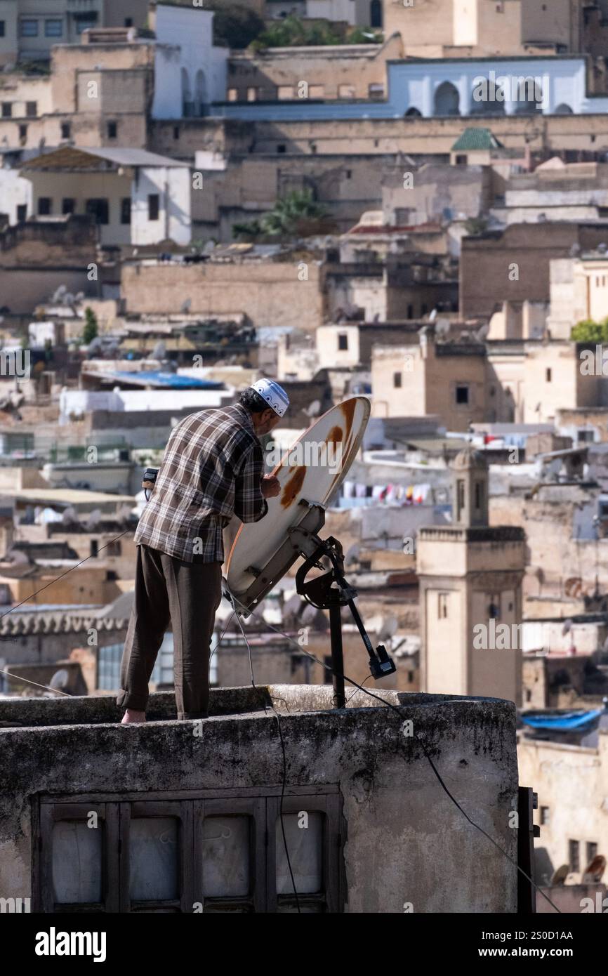 Man repairing a satellite dish with in backdrop the landscape of the ...