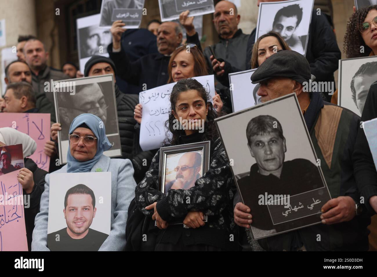 Wafaa Mustafa, center, holds a picture of her missing father during a ...
