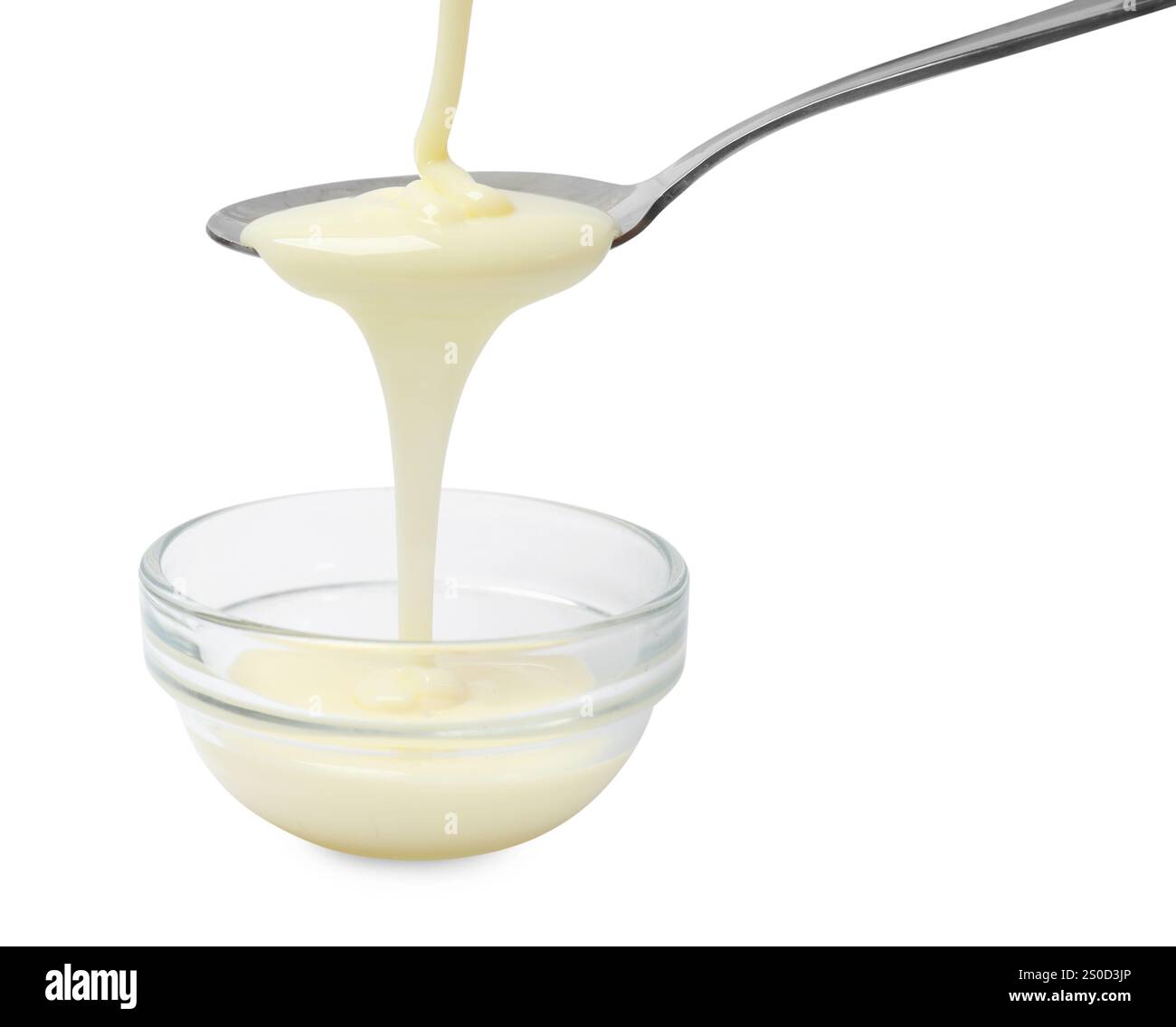 Condensed milk flowing down from spoon into bowl isolated on white ...