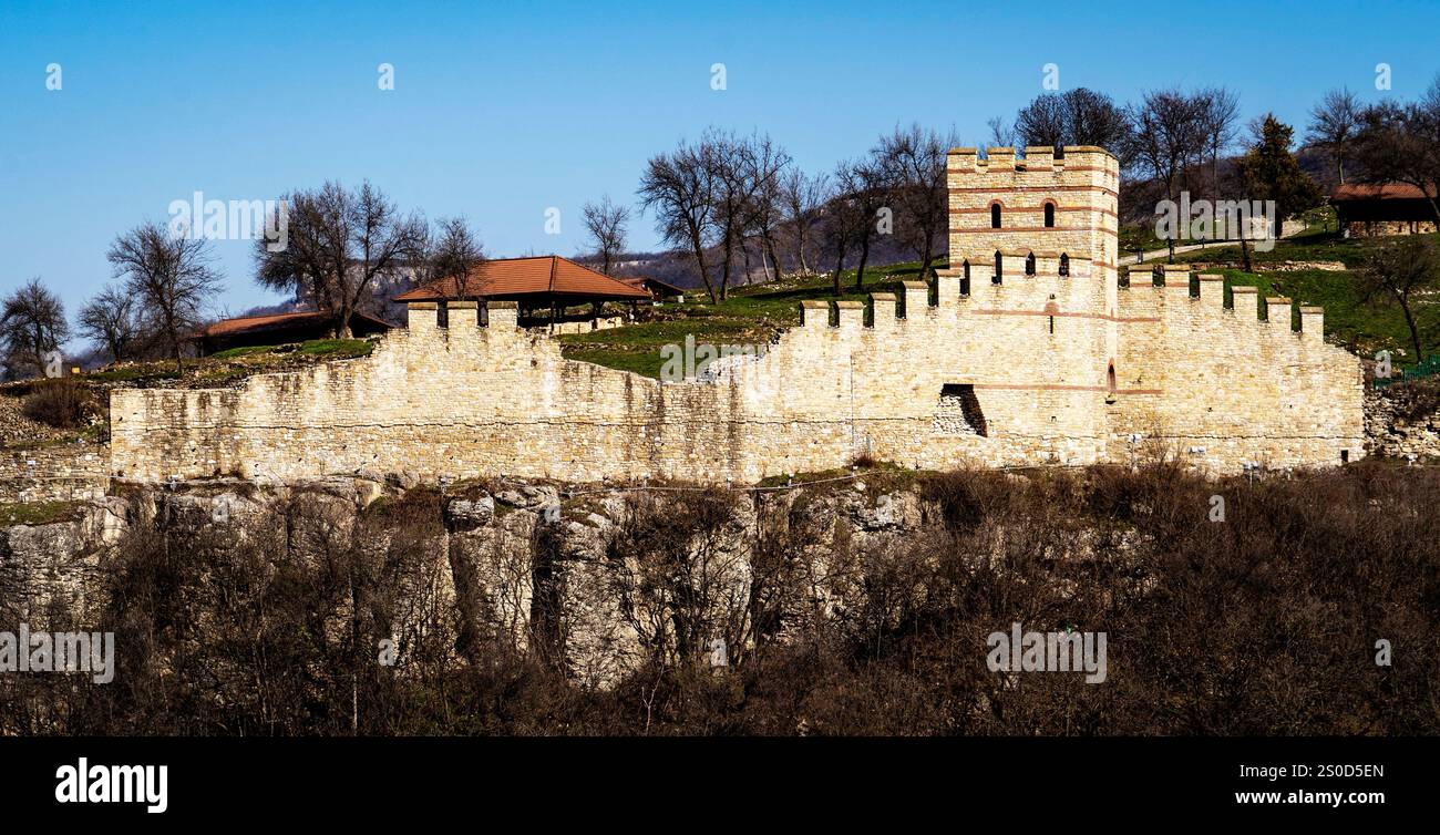 A medieval stone fortress with crenellated walls and a tower, set on a ...