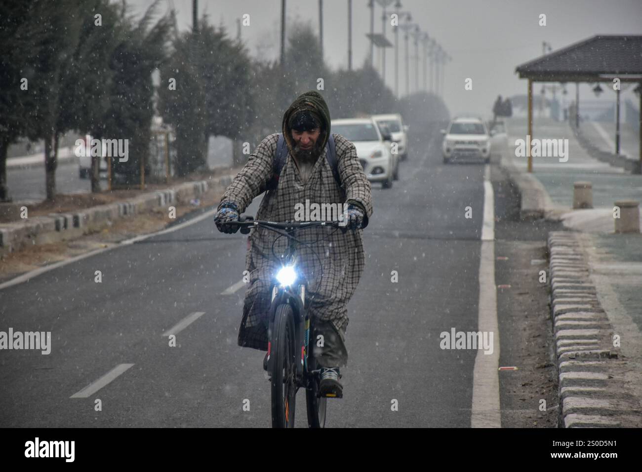 A cyclist rides along the snow covered road during seasons first snowfall in Srinagar, the ...
