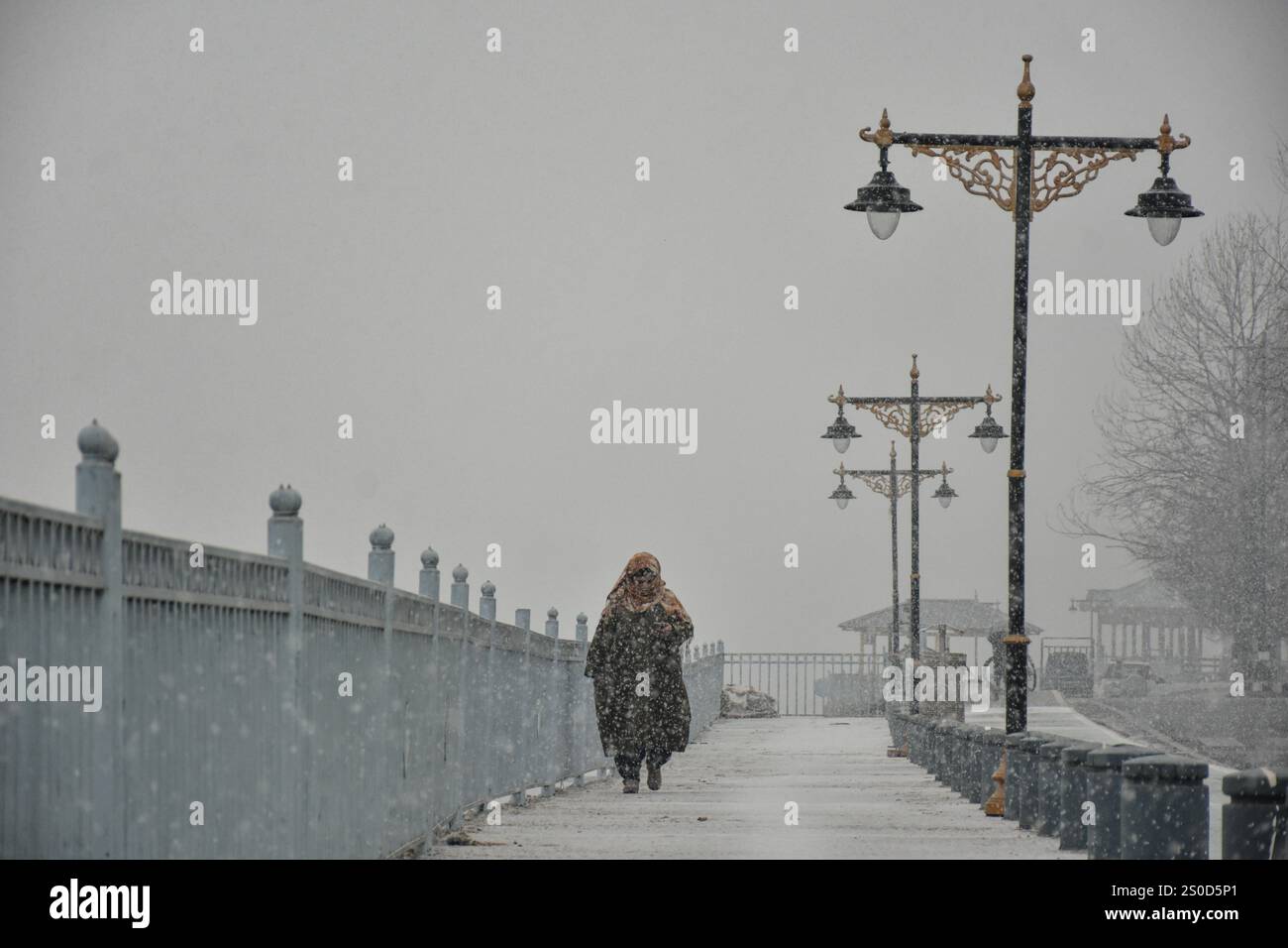 A commuter walks along the snow covered street during seasons first ...