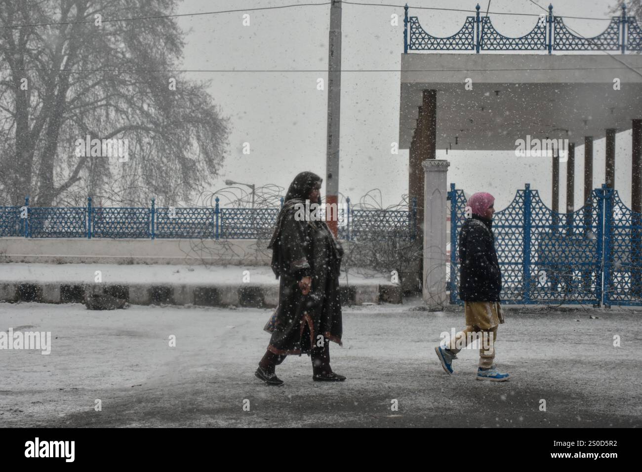 Commuters walk along the snow covered road during seasons first ...
