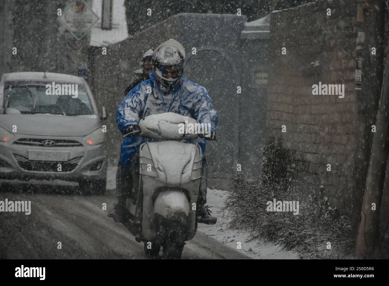 A man rides a scooter along the snow covered road during seasons first ...