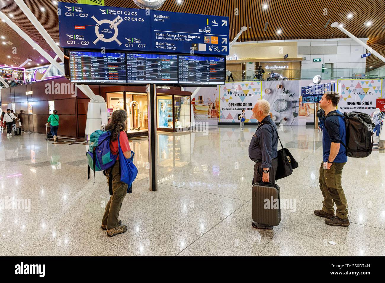 Travellers reading information sign at airport, Kuala Lumpur, Malaysia ...