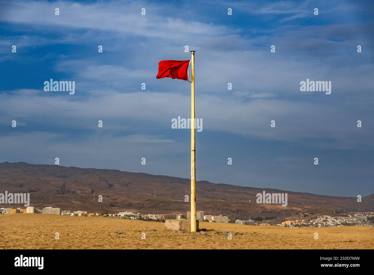 The frayed red flag in the dunes is fluttering in the coastal wind ...
