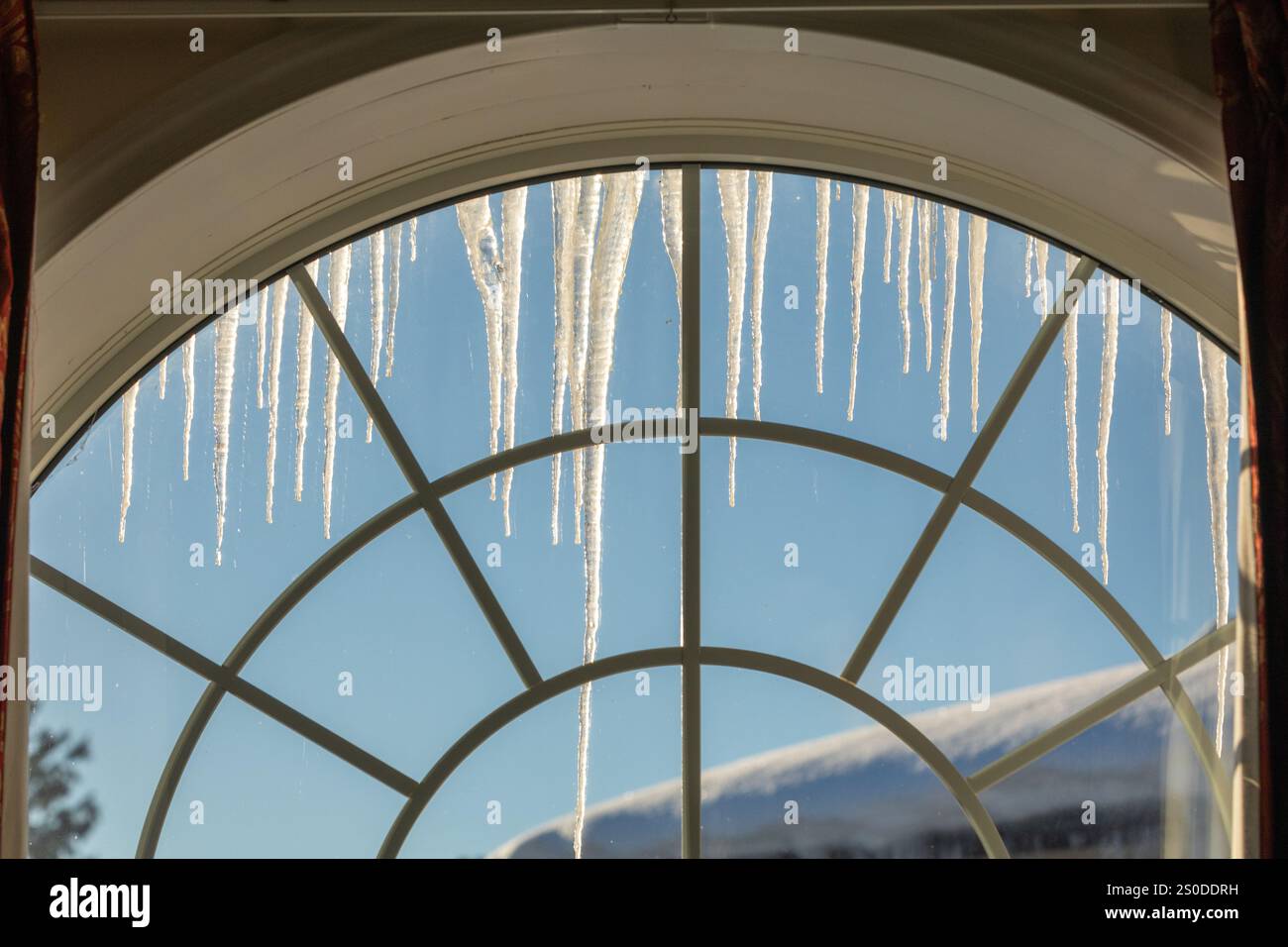 Icicles, seen through window, hang from eaves Stock Photo - Alamy