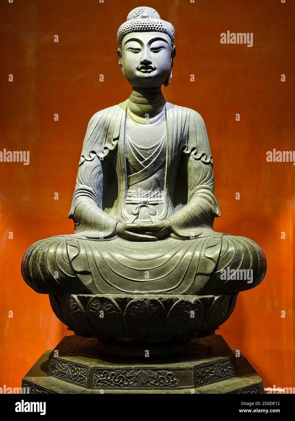 A statue of a person sitting on a lotus flower. The statue is black and ...
