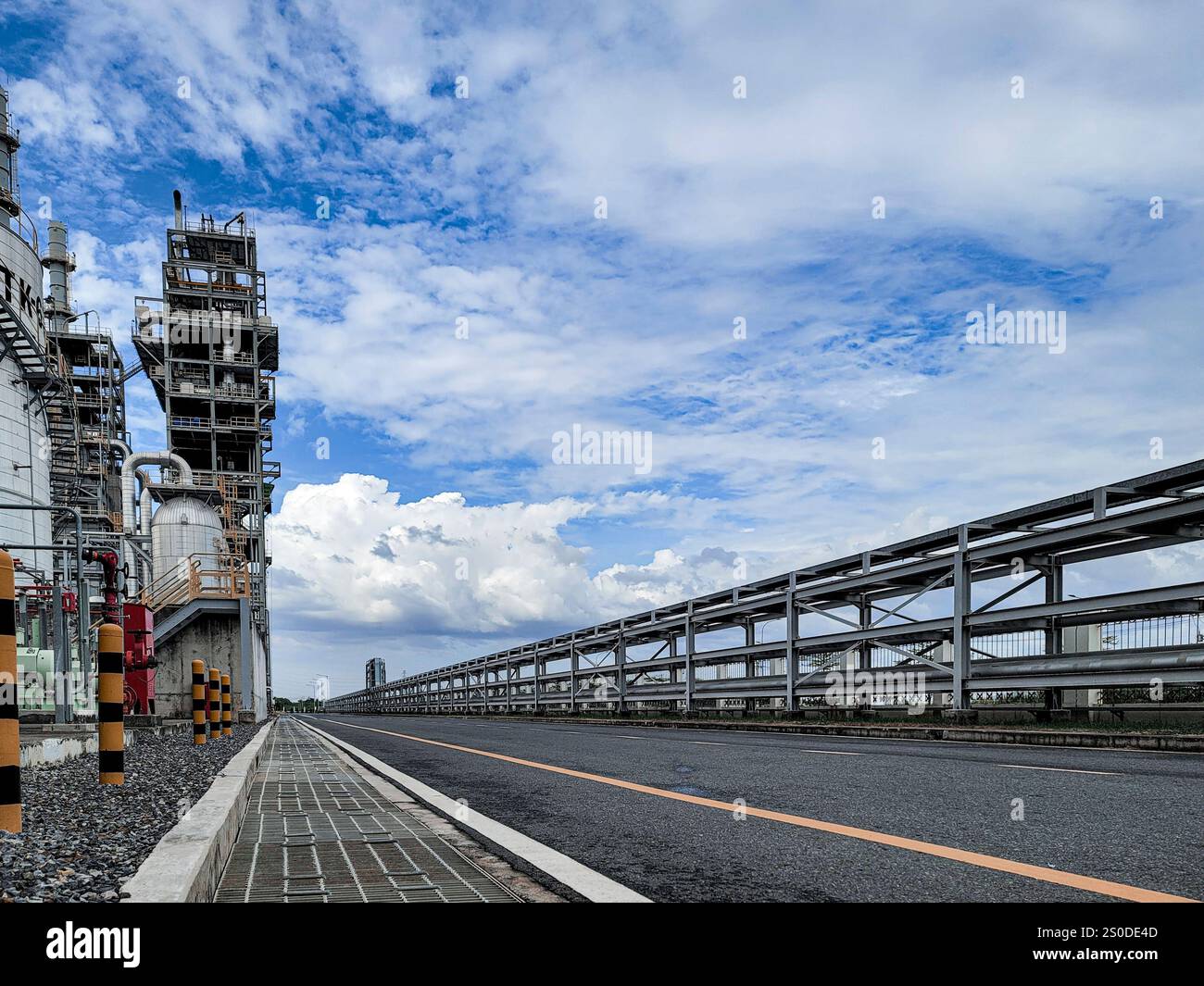 A long road with a fence on the side. The fence is made of metal. There ...