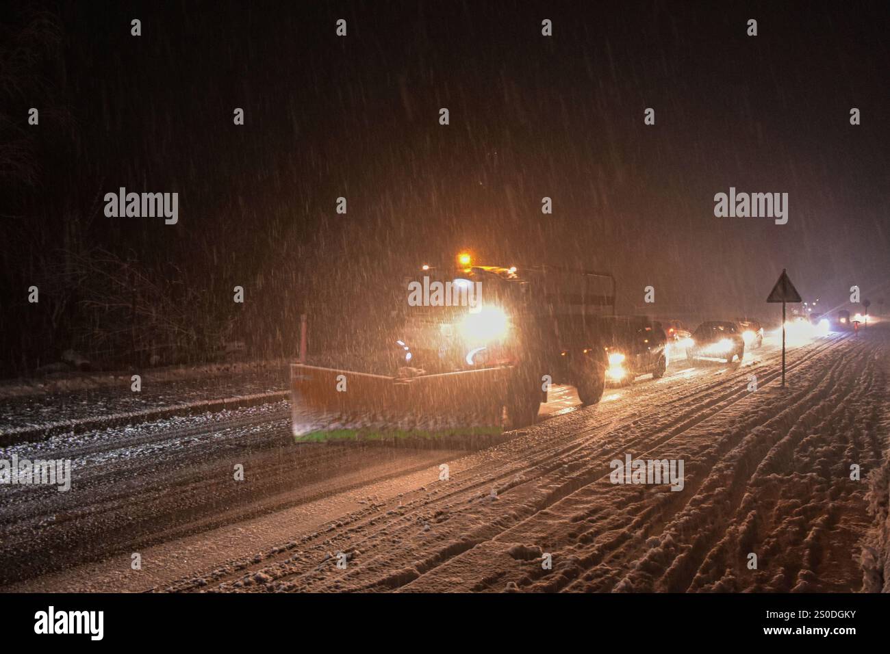 A snow machine clears snow from the road during snowfall in Srinagar ...