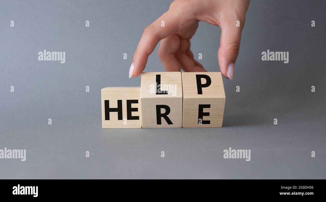 Help is here symbol. Businessman hand Turns cube and changes word Here ...