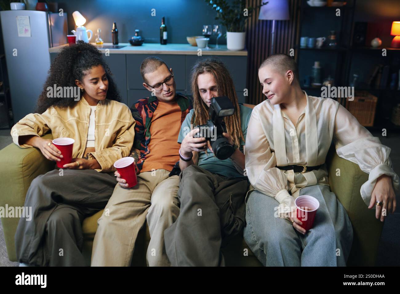 Friends sitting on sofa and watching photos from party on camera Stock ...