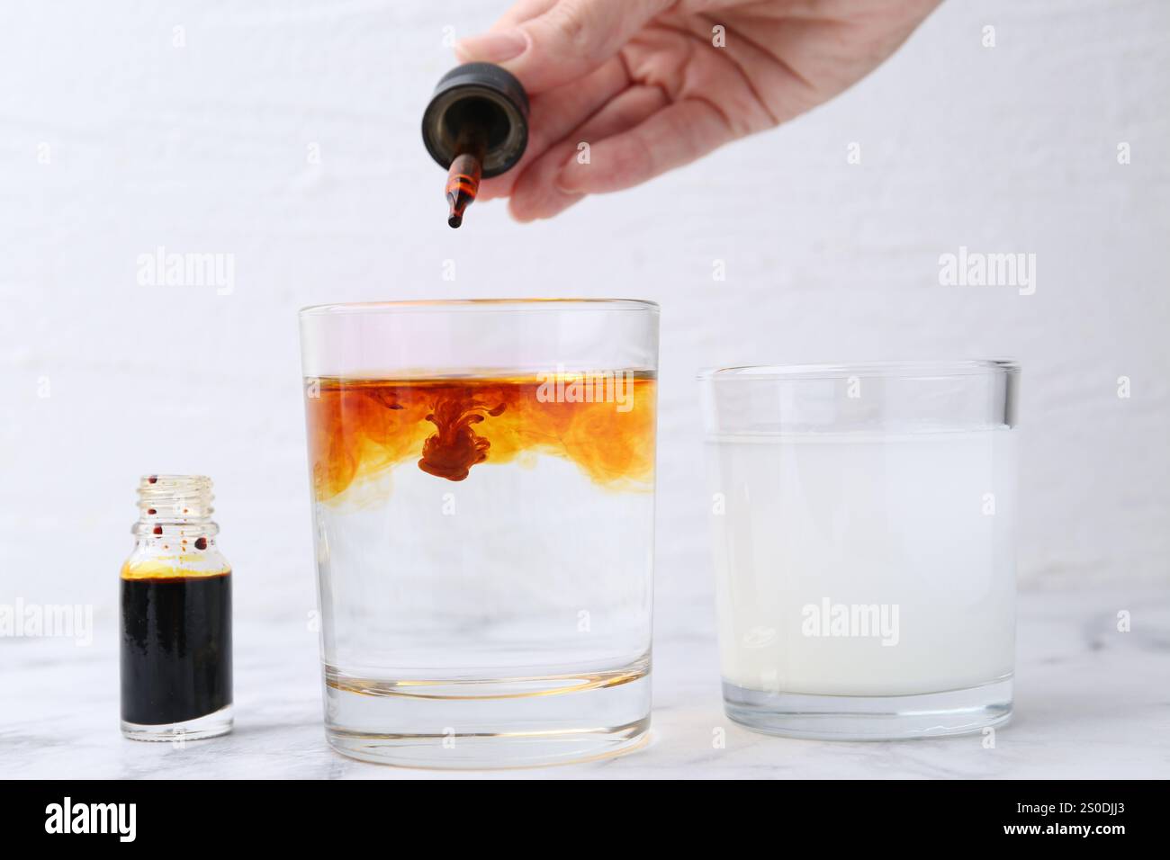 Iodine starch test. Woman dripping aqueous iodine into glass of water ...