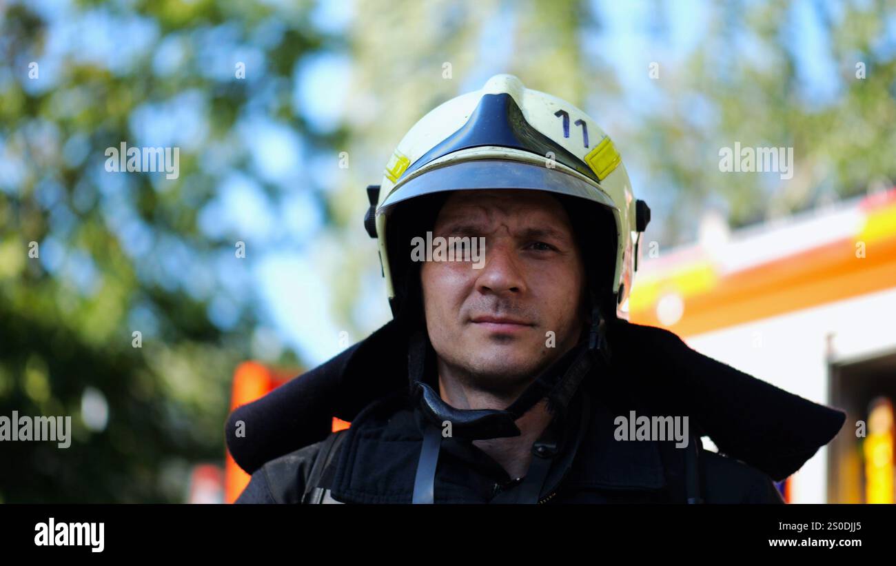 Portrait of confident male fireguard with dirty face standing near a ...
