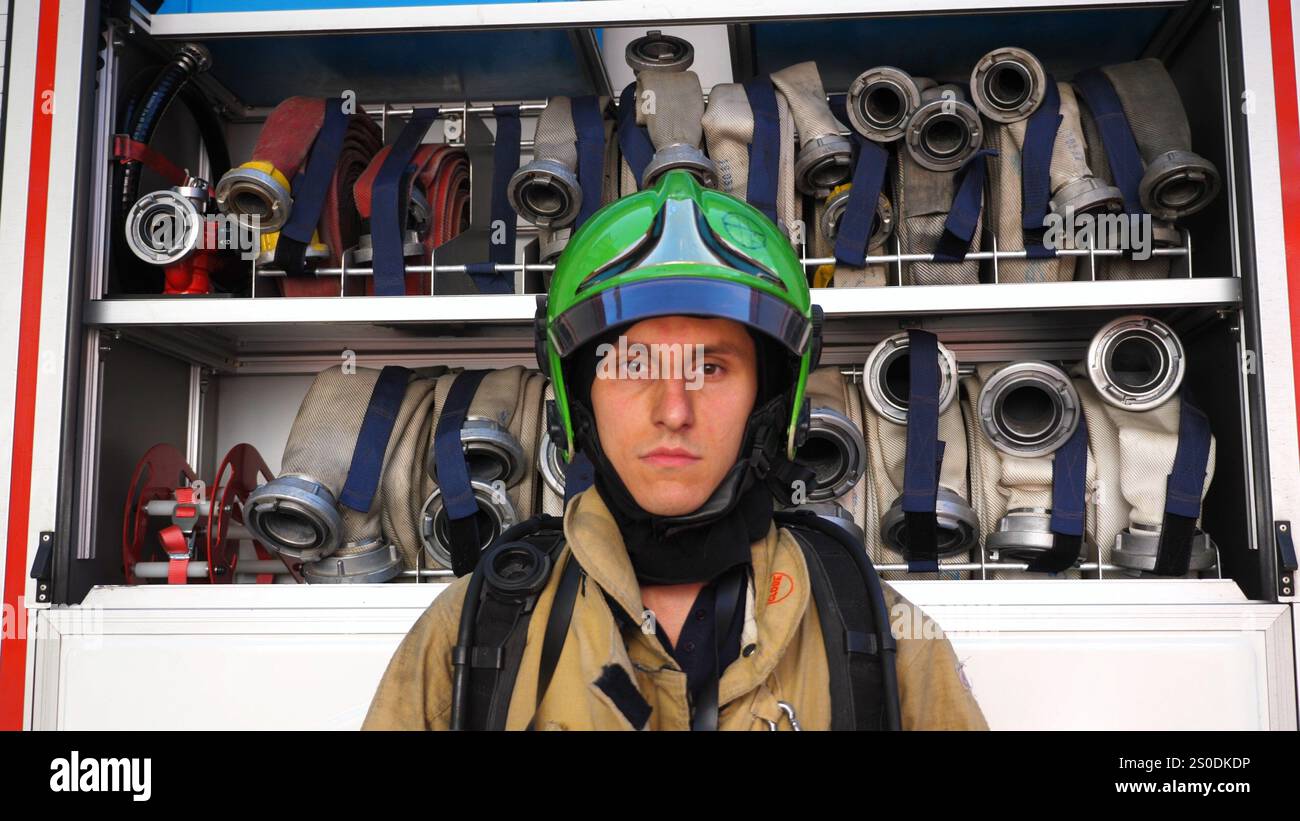 Portrait of tired male firefighter standing near a fire engine. Young ...