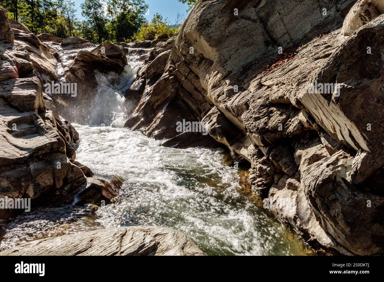 A river flows through a rocky canyon. The water is clear and the rocks ...