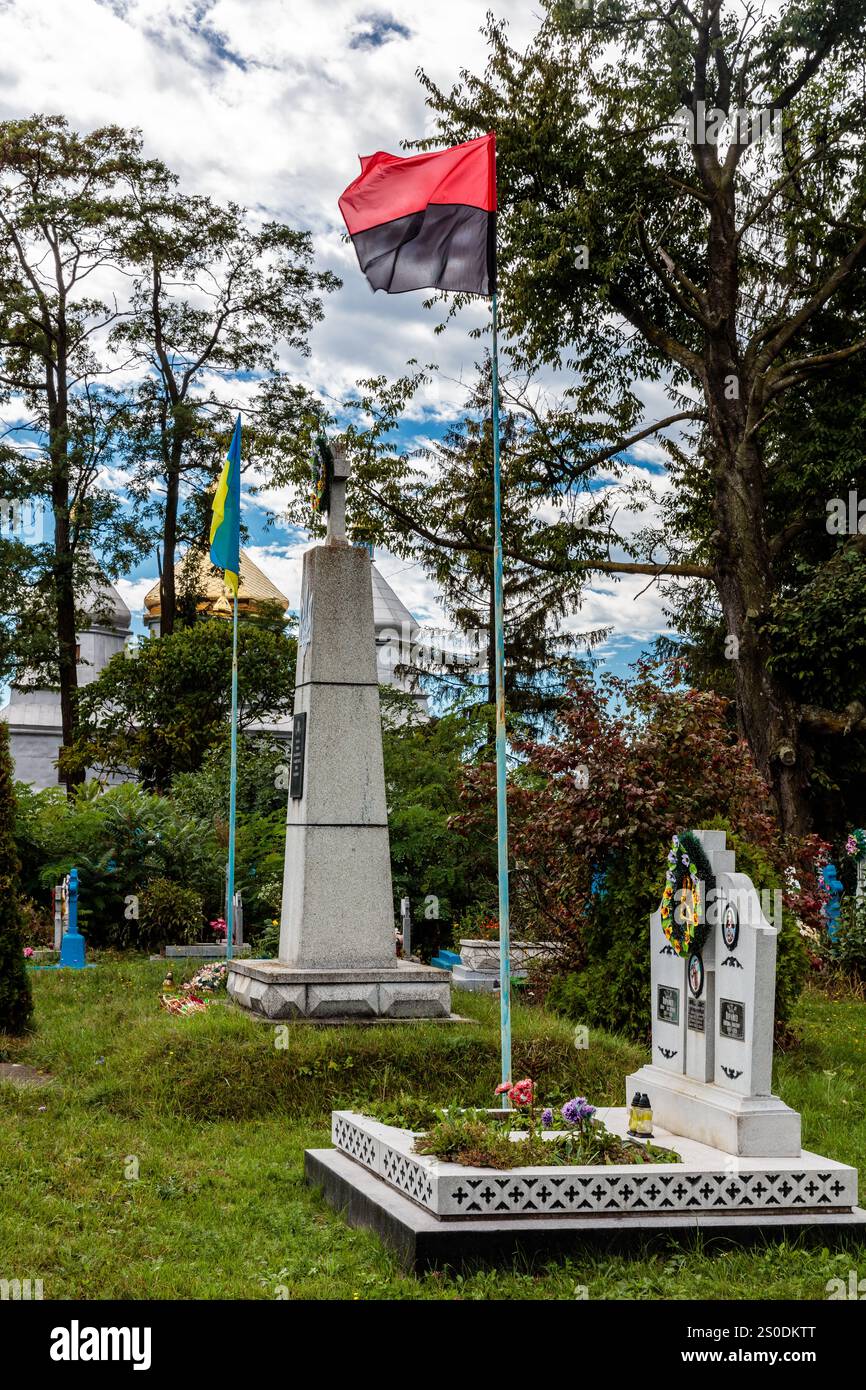 A cemetery with a white headstone and a red and white flag. The flag is ...