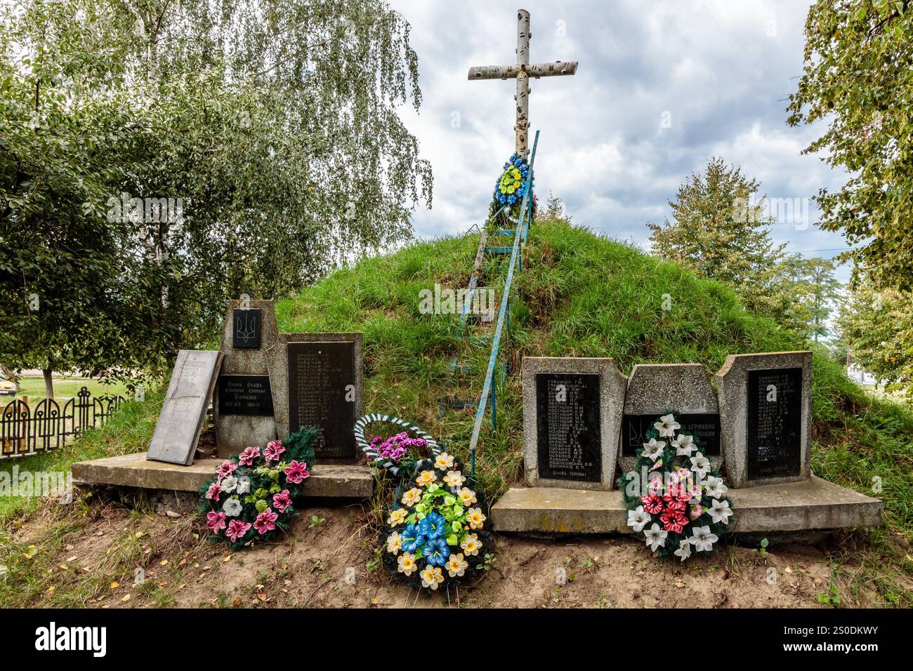 A cemetery with a cross and flowers on top of a hill. The flowers are ...
