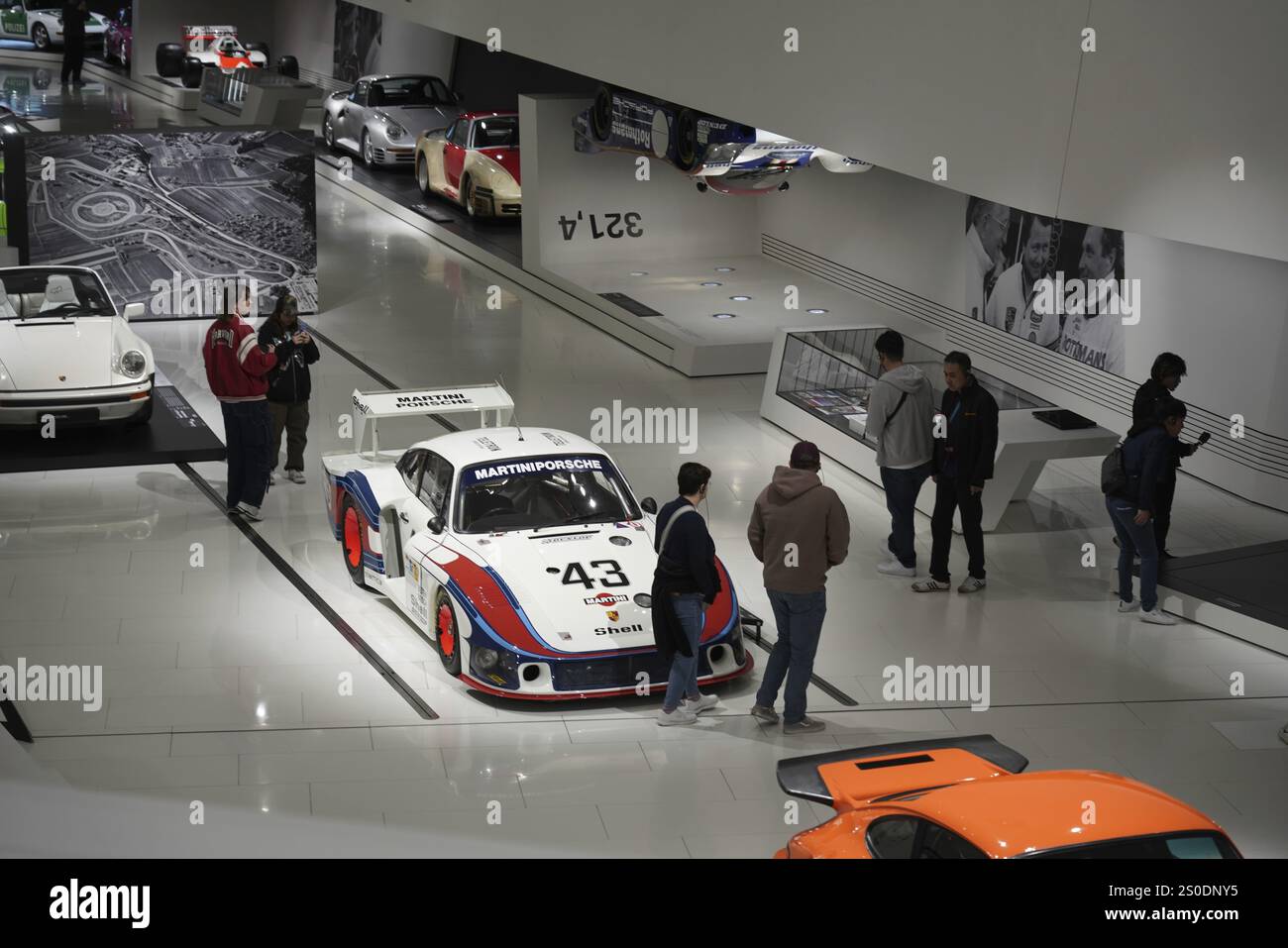 Museum exhibition with a Porsche racing car surrounded by visitors and ...