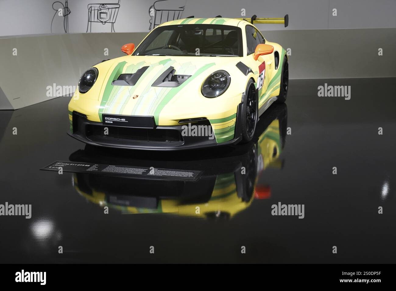 Yellow Porsche racing car with green stripes stands on reflective floor ...