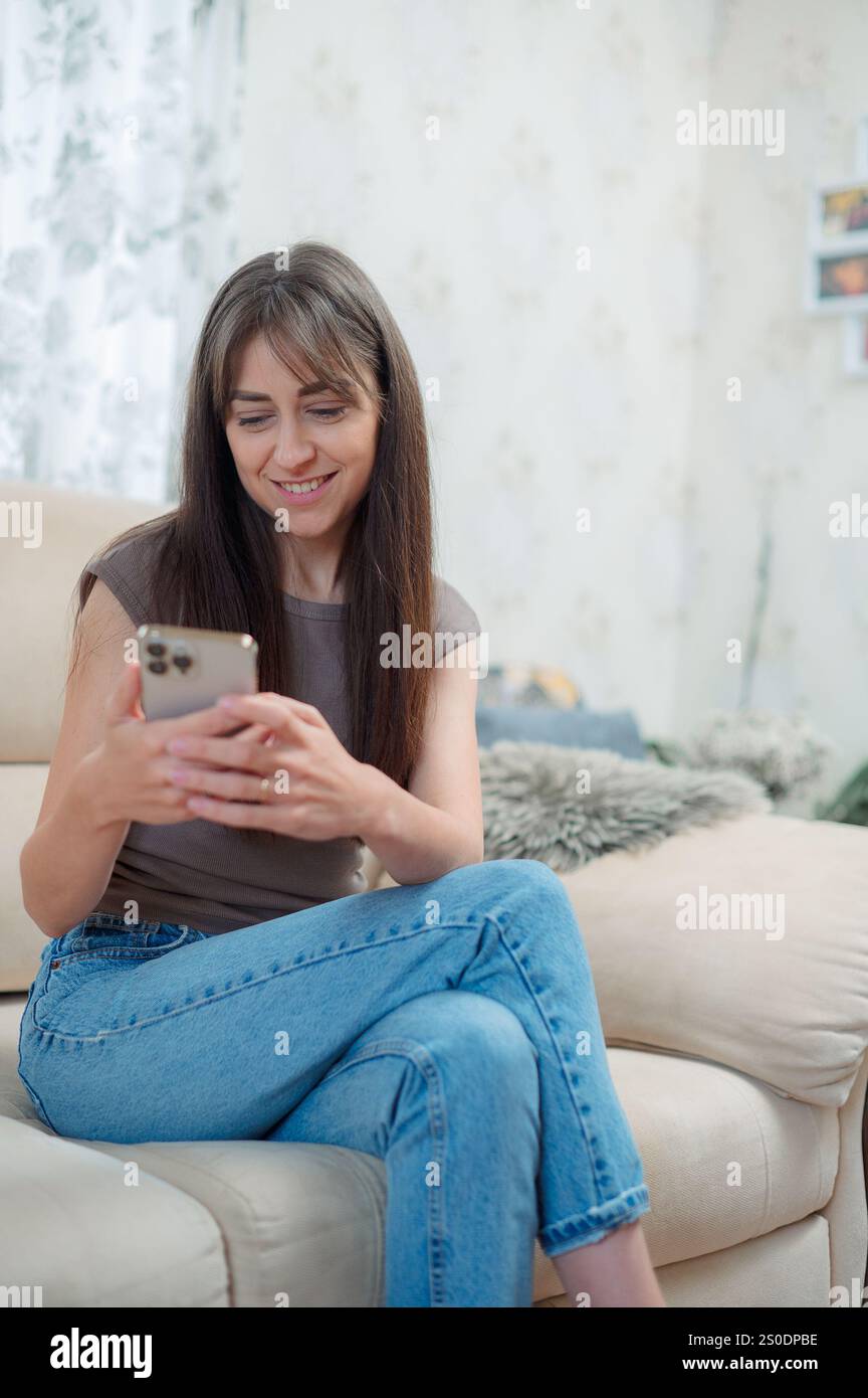 Casual young woman making a phone call while sitting comfortably on a ...