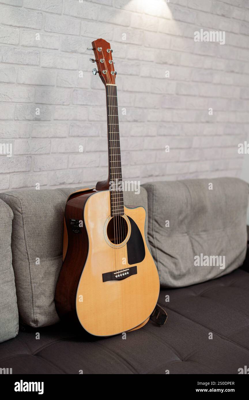 Beautiful six-string acoustic guitar, wood body, on sofa in studio ...