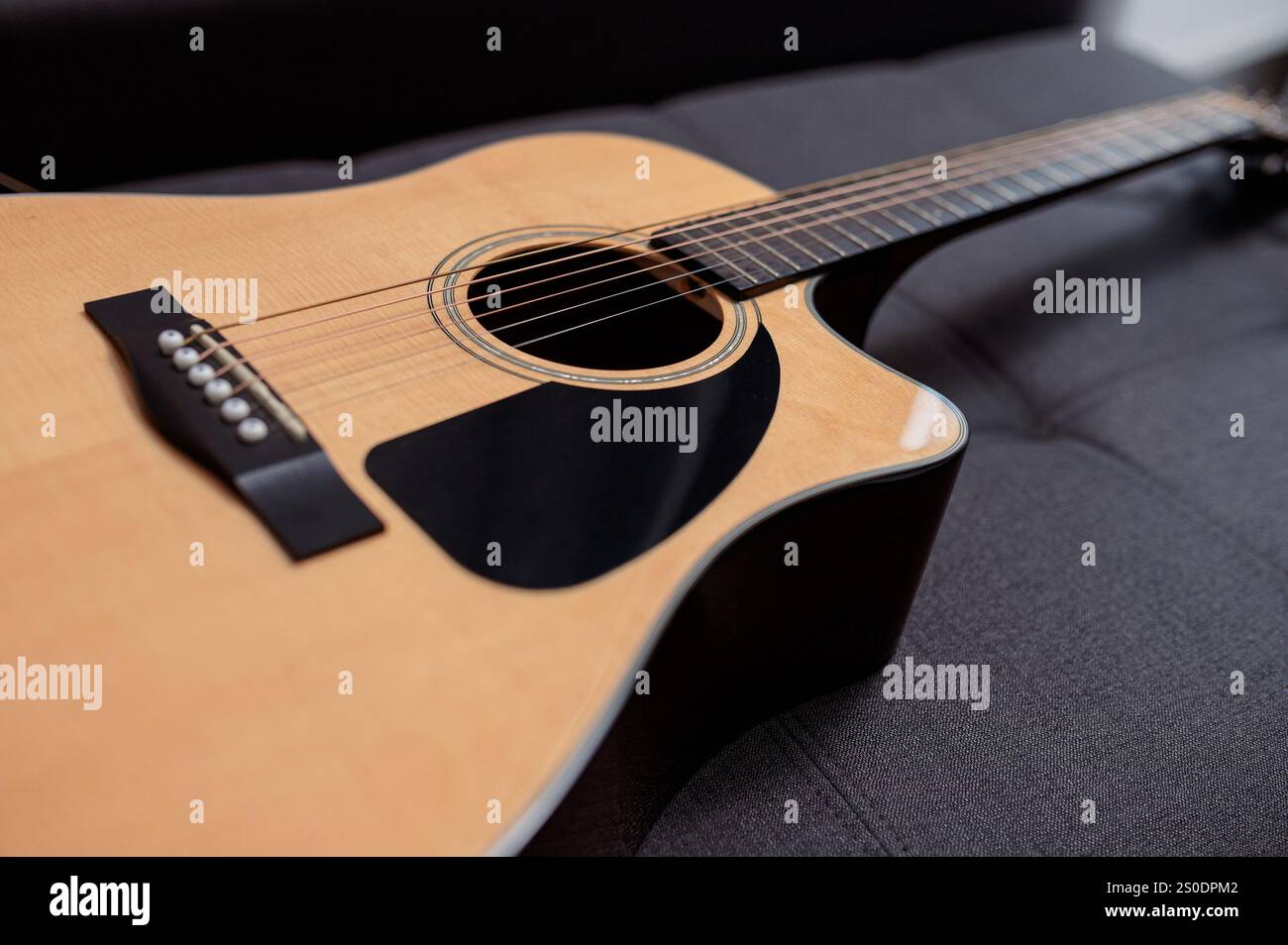 Beautiful six-string acoustic guitar, wood body, on sofa in studio ...