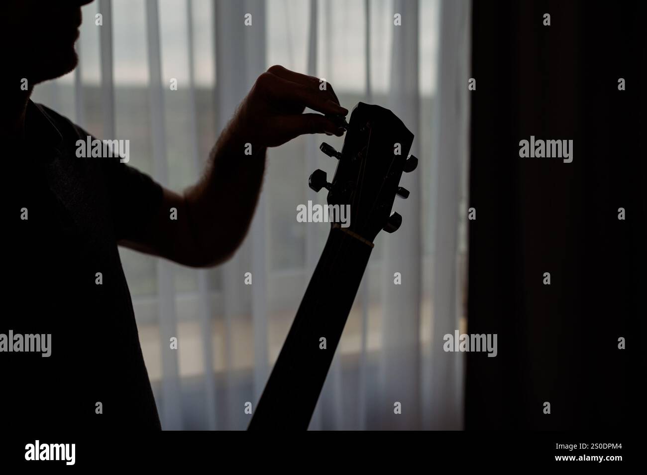 Silhouette of guitarist paying a acoustic guitar against window. Man ...