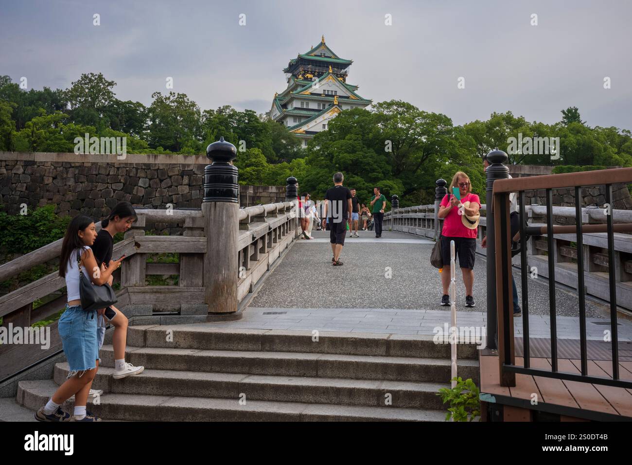 Osaka, Japan, Jun 23, 2024: Tourist cross a bridge over the inner moat ...