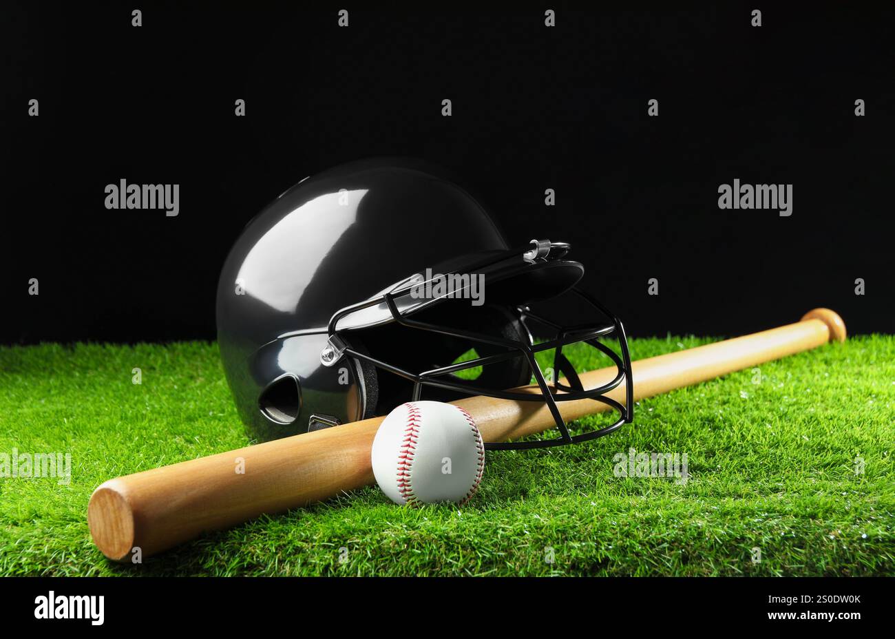 Baseball helmet, bat and ball on artificial grass against black ...