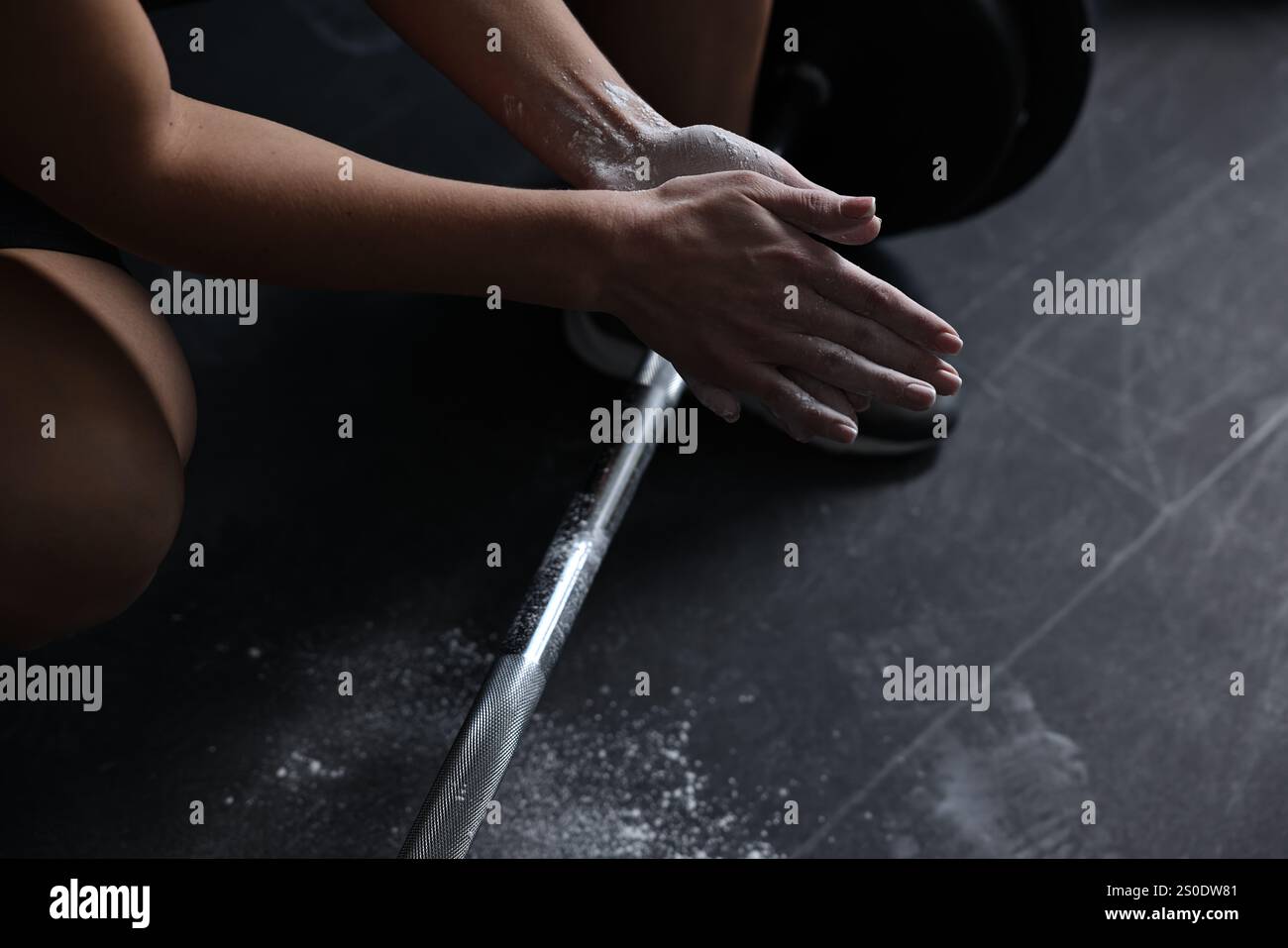 Woman clapping hands with talcum powder before training with barbell in ...
