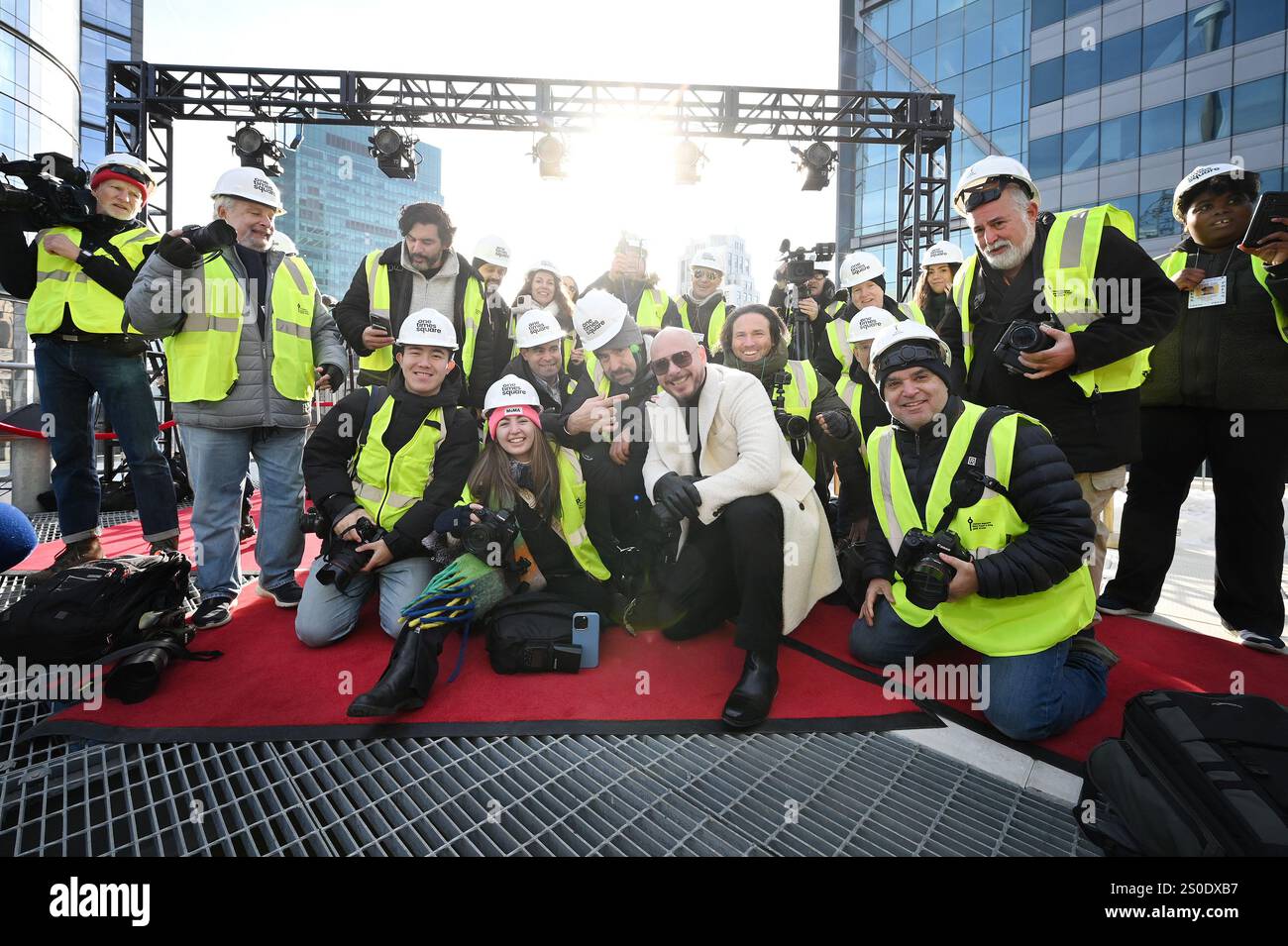 Singer and rapper Pitbull (white coat) poses with members of the media ...