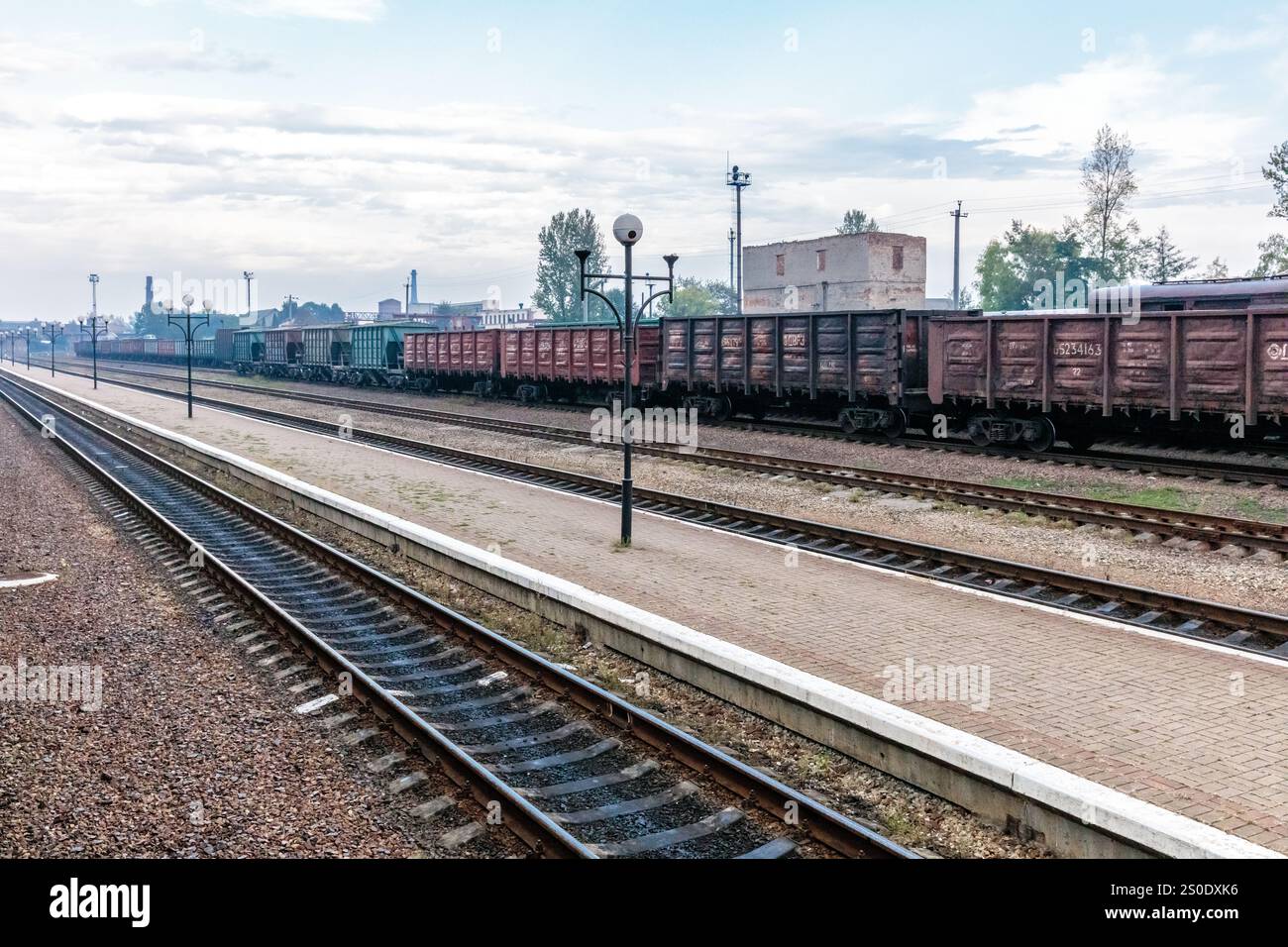 A train station with a few trains on the tracks. The trains are mostly ...