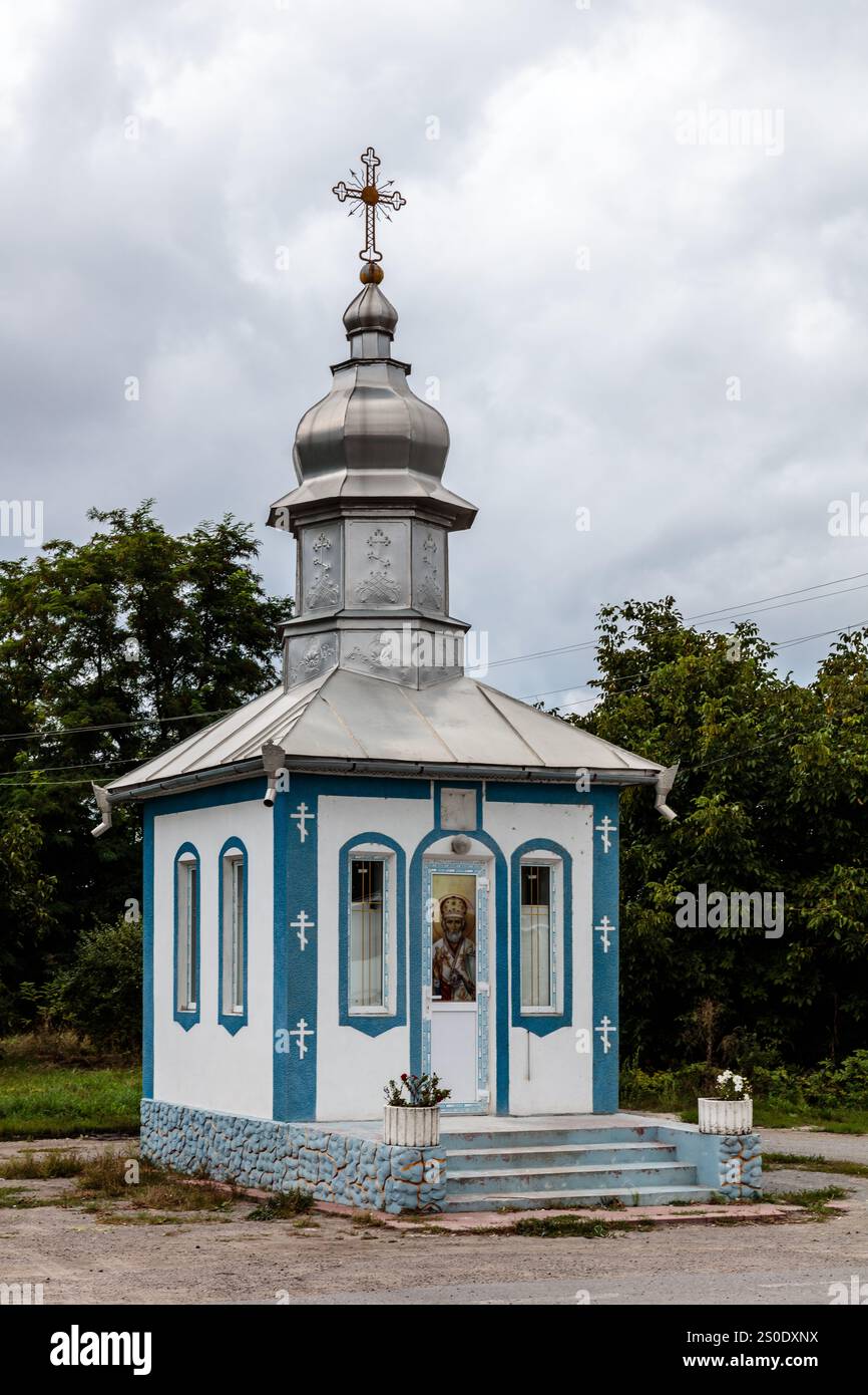A small blue and white church with a cross on top. The church is ...