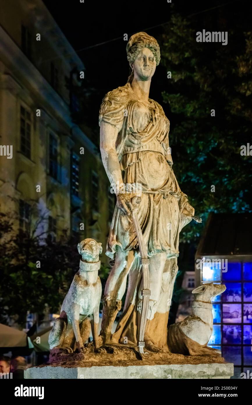 A statue of a woman holding a sword and two dogs. The statue is ...
