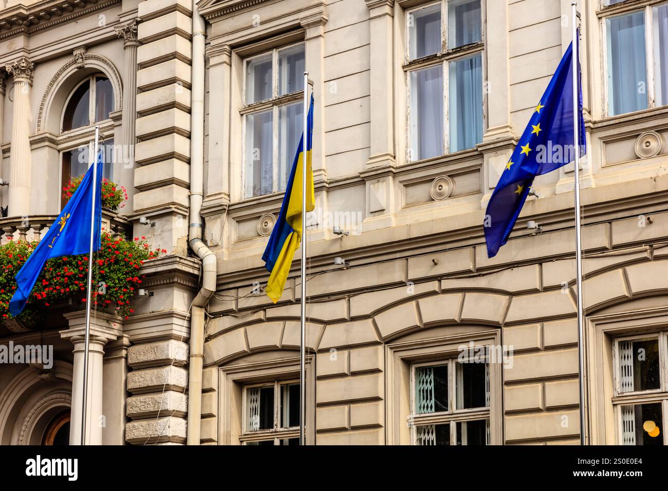 Three flags are hanging from the top of a building. The flags are blue ...