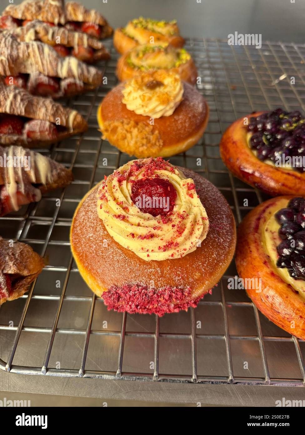 Berliner donut with whipped cream and cherry topping on wire rack for ...
