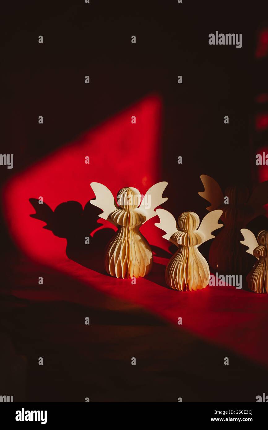 DIY white paper angels in the dark on red background. Religious symbols ...