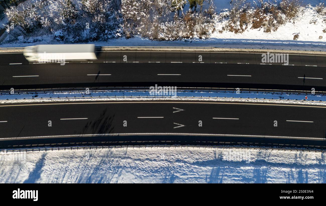 A top-down perspective of a highway surrounded by snow-covered terrain ...