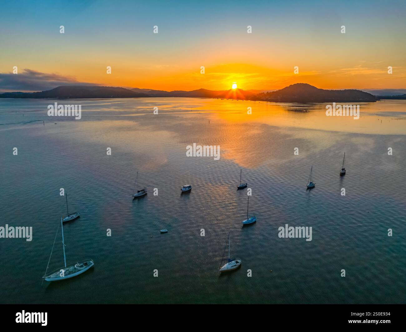 Aerial sunrise waterscape with boats, reflections and some fog around ...