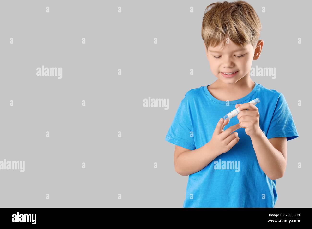 Little diabetic boy using lancet pen on grey background Stock Photo - Alamy