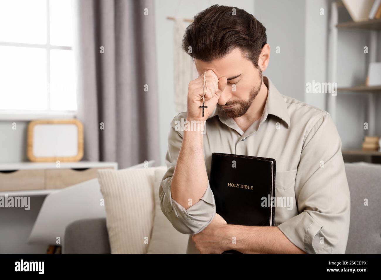 Religious man with Bible praying at home Stock Photo - Alamy
