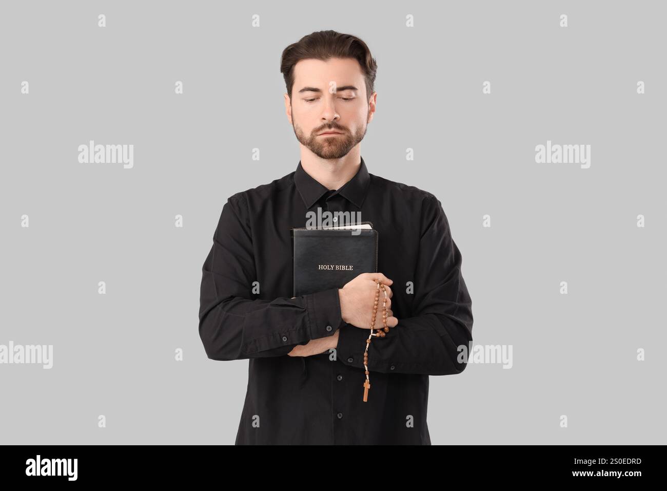 Religious man with Bible praying on grey background Stock Photo - Alamy