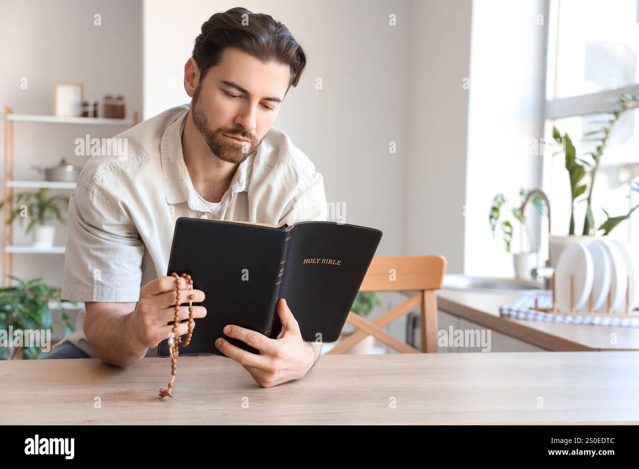 Religious man reading Bible at home Stock Photo - Alamy