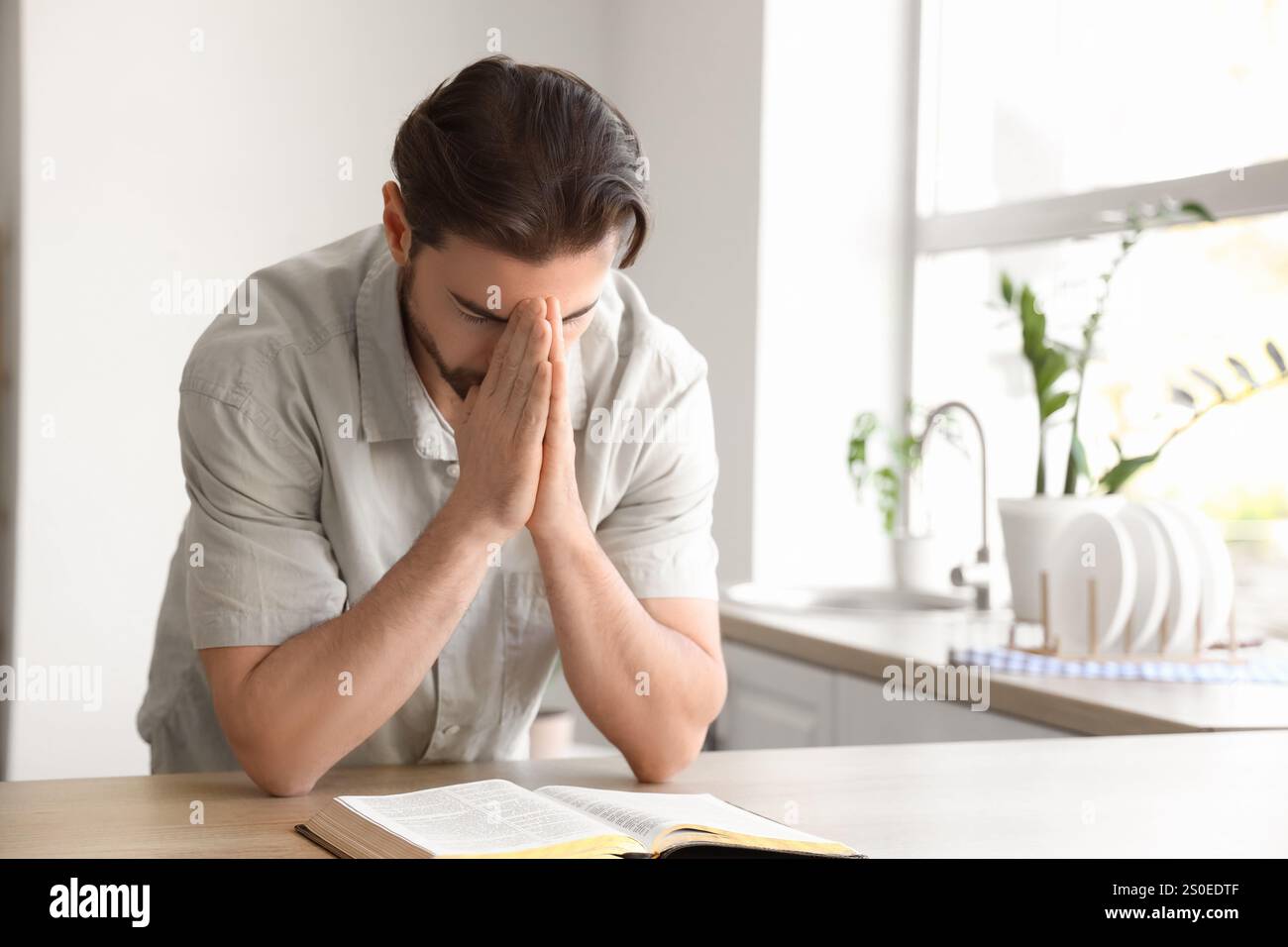 Religious man with Bible praying at home Stock Photo - Alamy