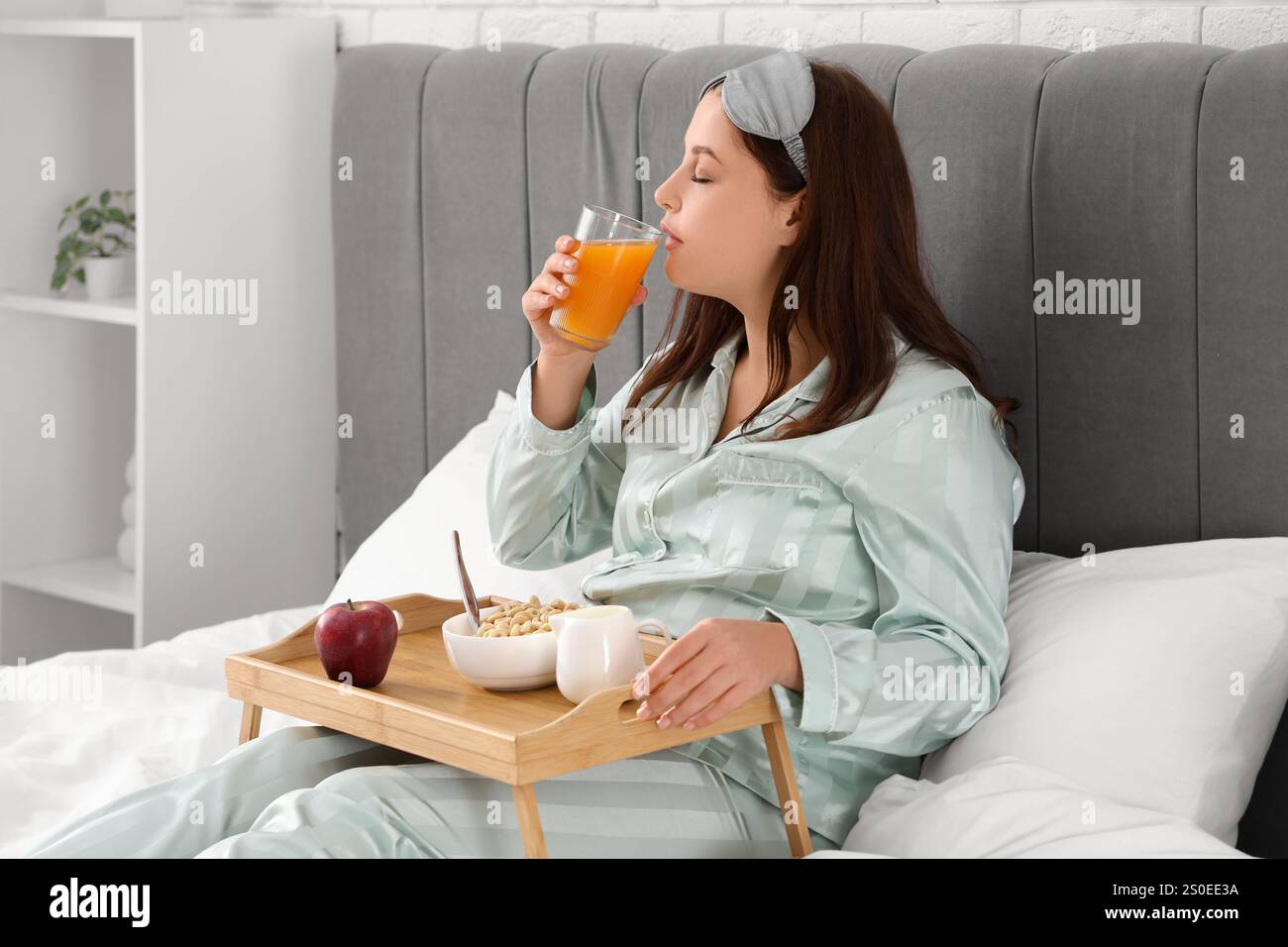 Beautiful young woman eating breakfast in bed at morning Stock Photo - Alamy
