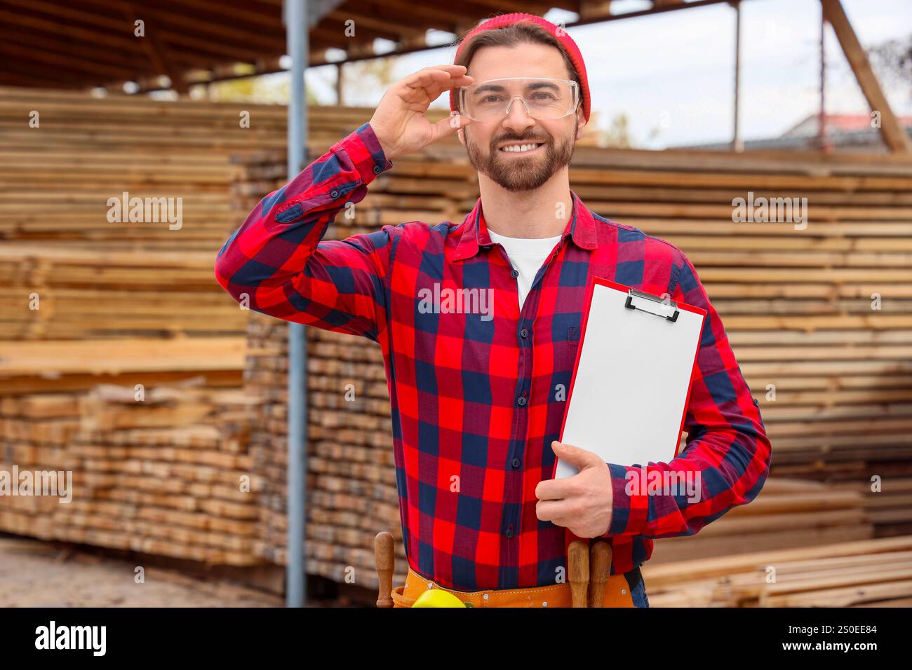 Male carpenter in safety goggles with clipboard at sawmill Stock Photo ...