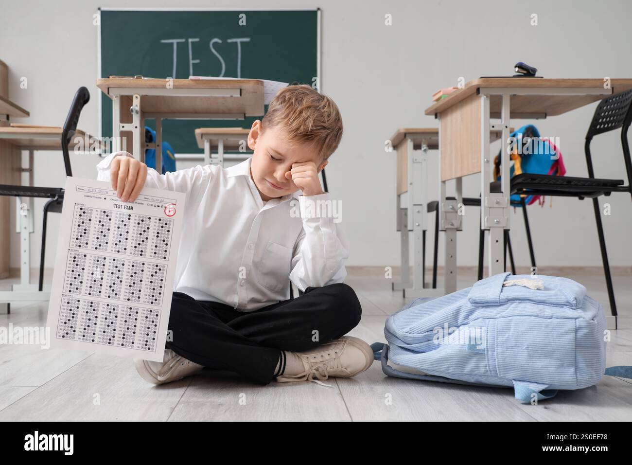 Upset schoolboy with results of test crying on floor in classroom Stock ...